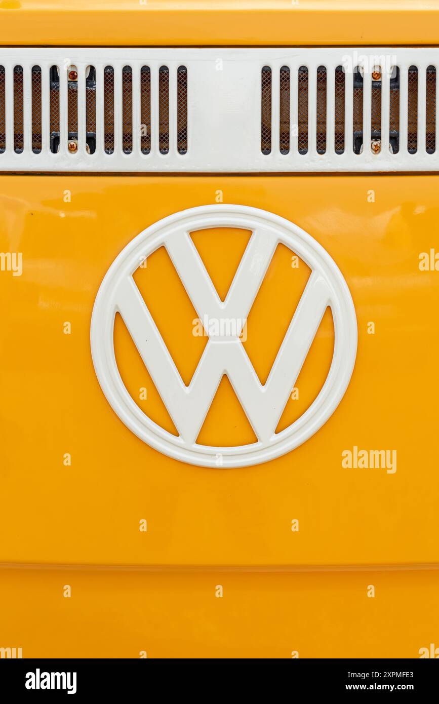 Symmetrical front view of a yellow VW camper van with company logo ...