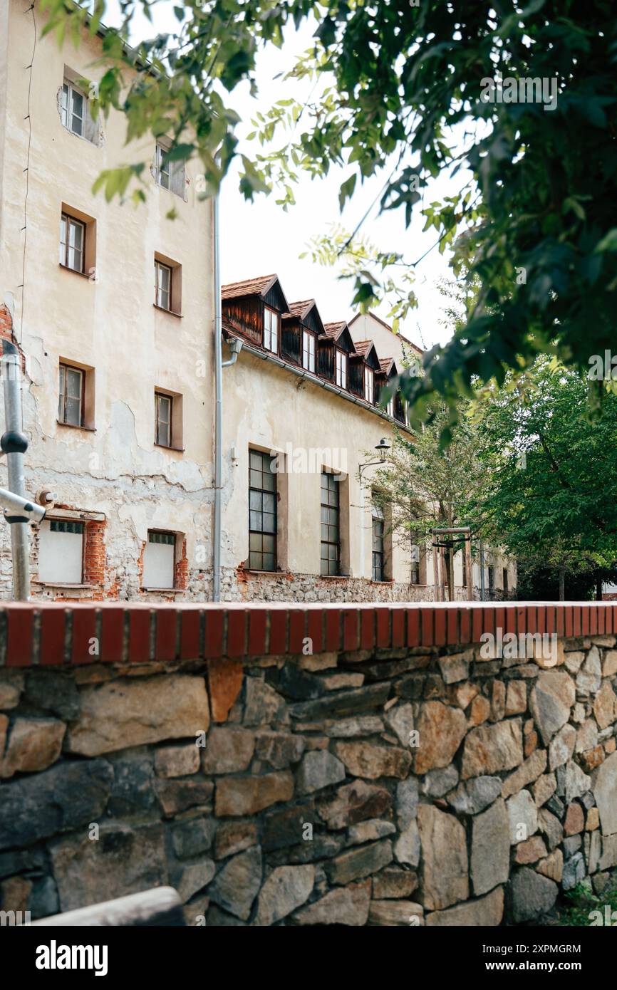 The setting features a weathered stone wall that encircles an old ...