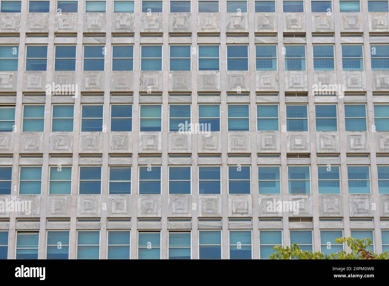 Modern building facade showing a repetitive pattern of windows, with a marble and concrete ...