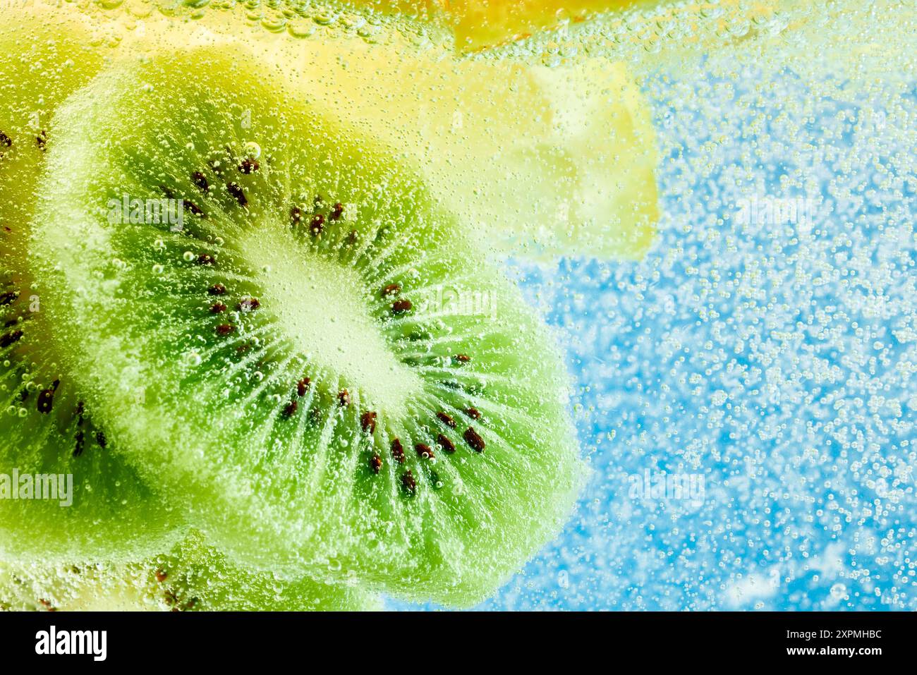 Slices of kiwi and lemon float in sparkling bubbles, creating ...