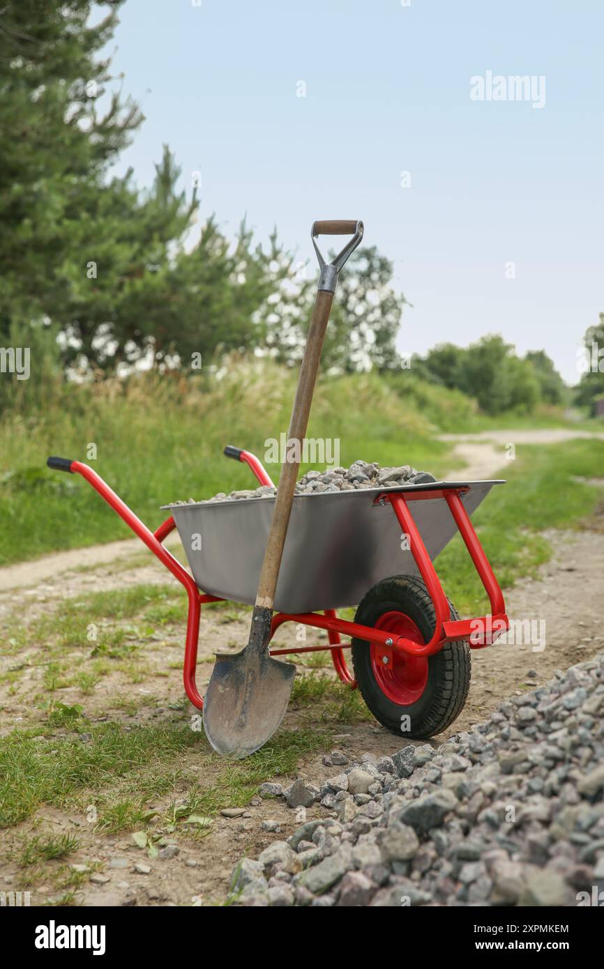 Wheelbarrow full of stones and shovel outdoors Stock Photo - Alamy