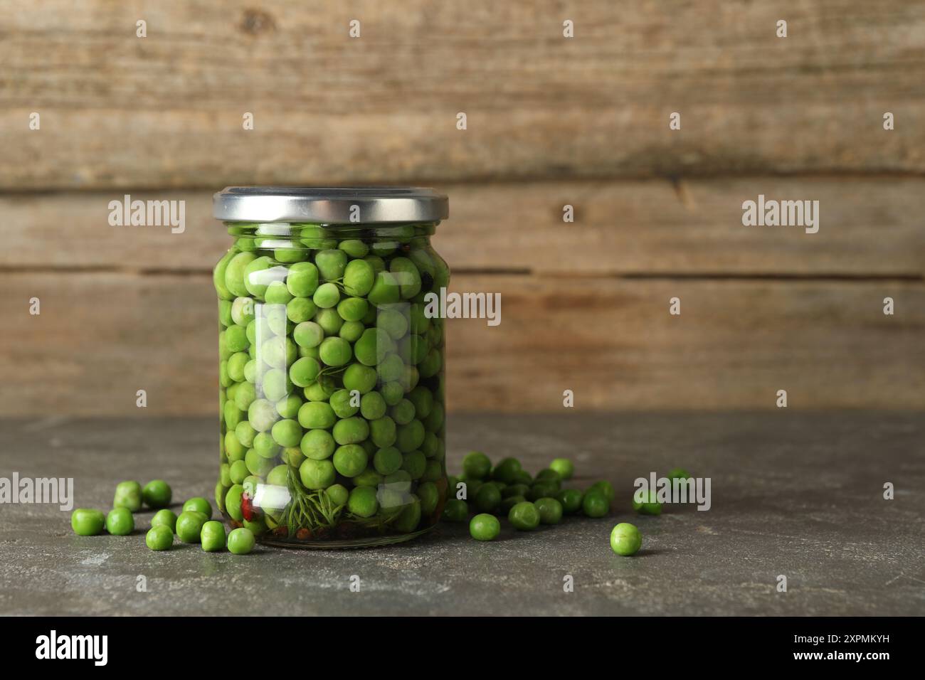 Tasty pickled green peas in jar on grey textured table, space for text ...