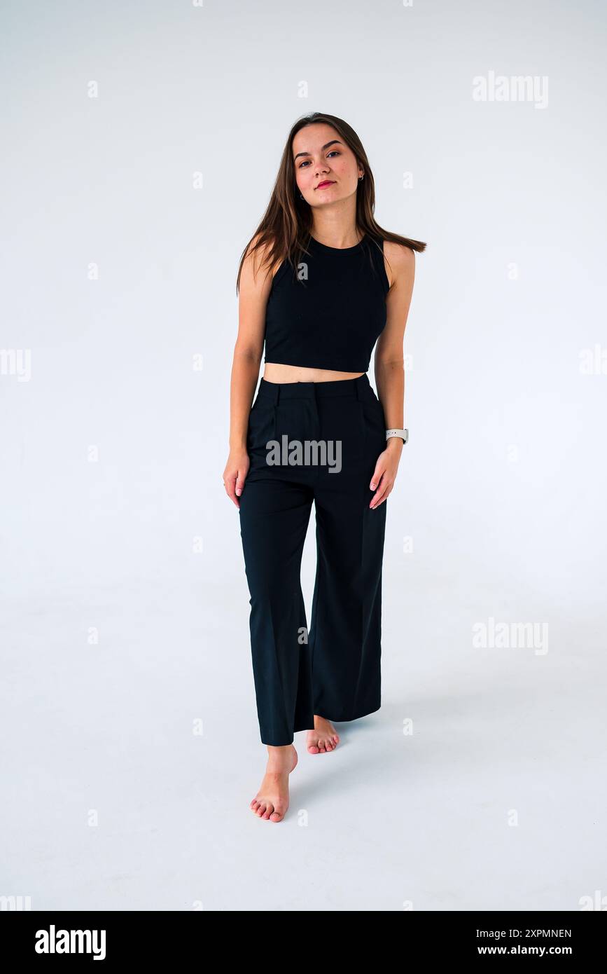a beautiful girl in black pants walks on a white floor Stock Photo - Alamy