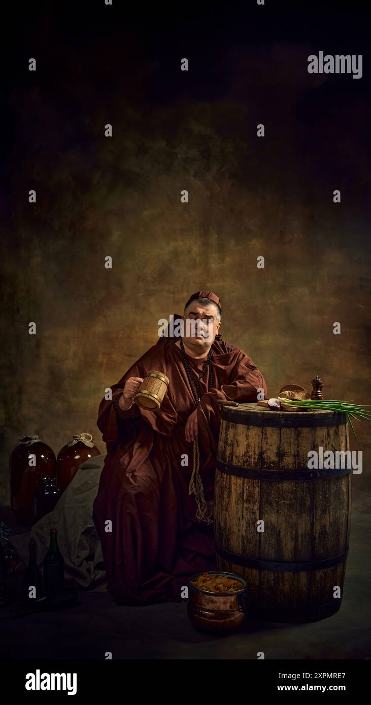 Man, medieval monk in monastic robes sitting in dark cellar, looking ...