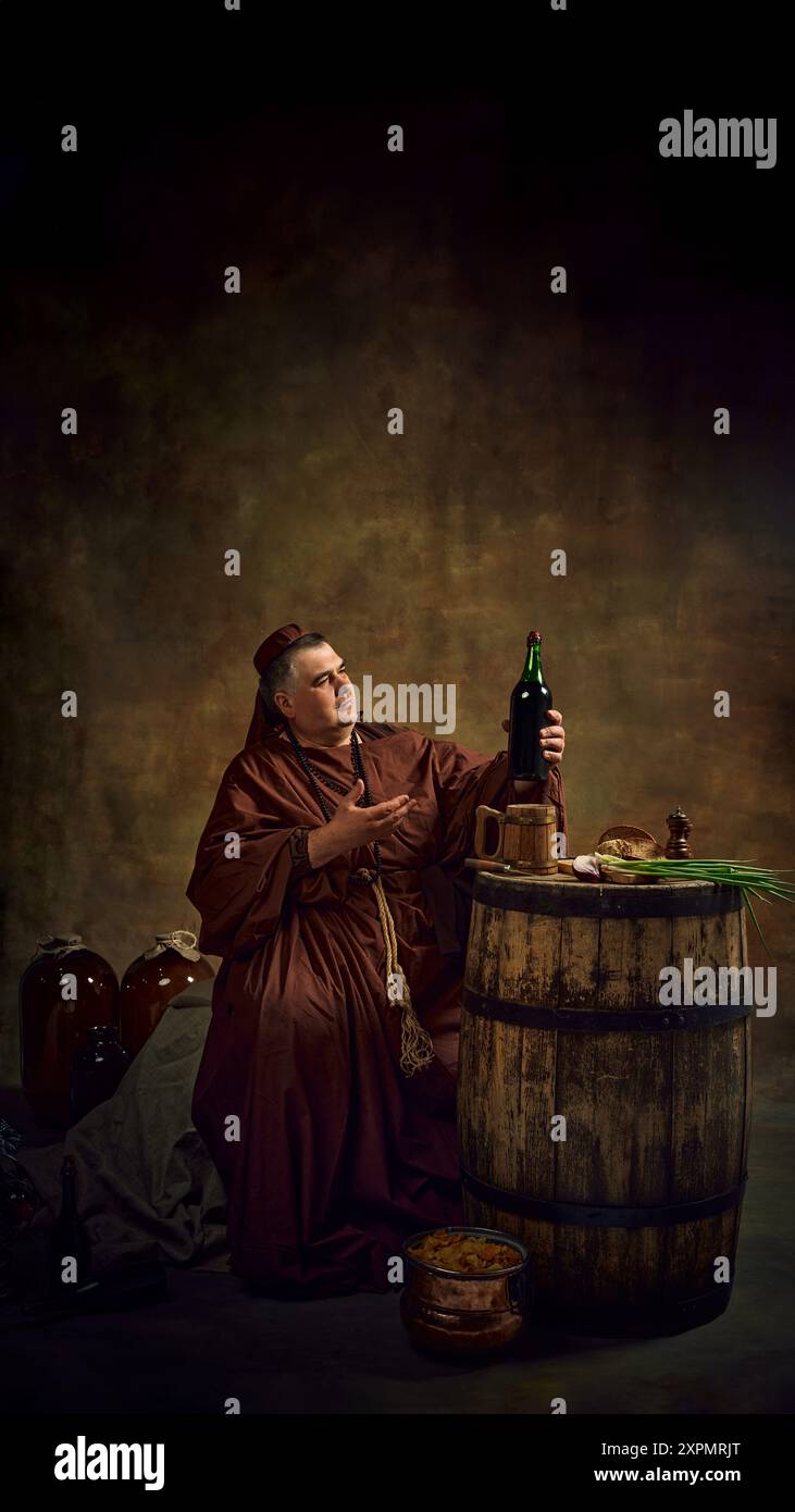 Medieval monk, man sitting surrounded by big glasses of wine and wooden ...