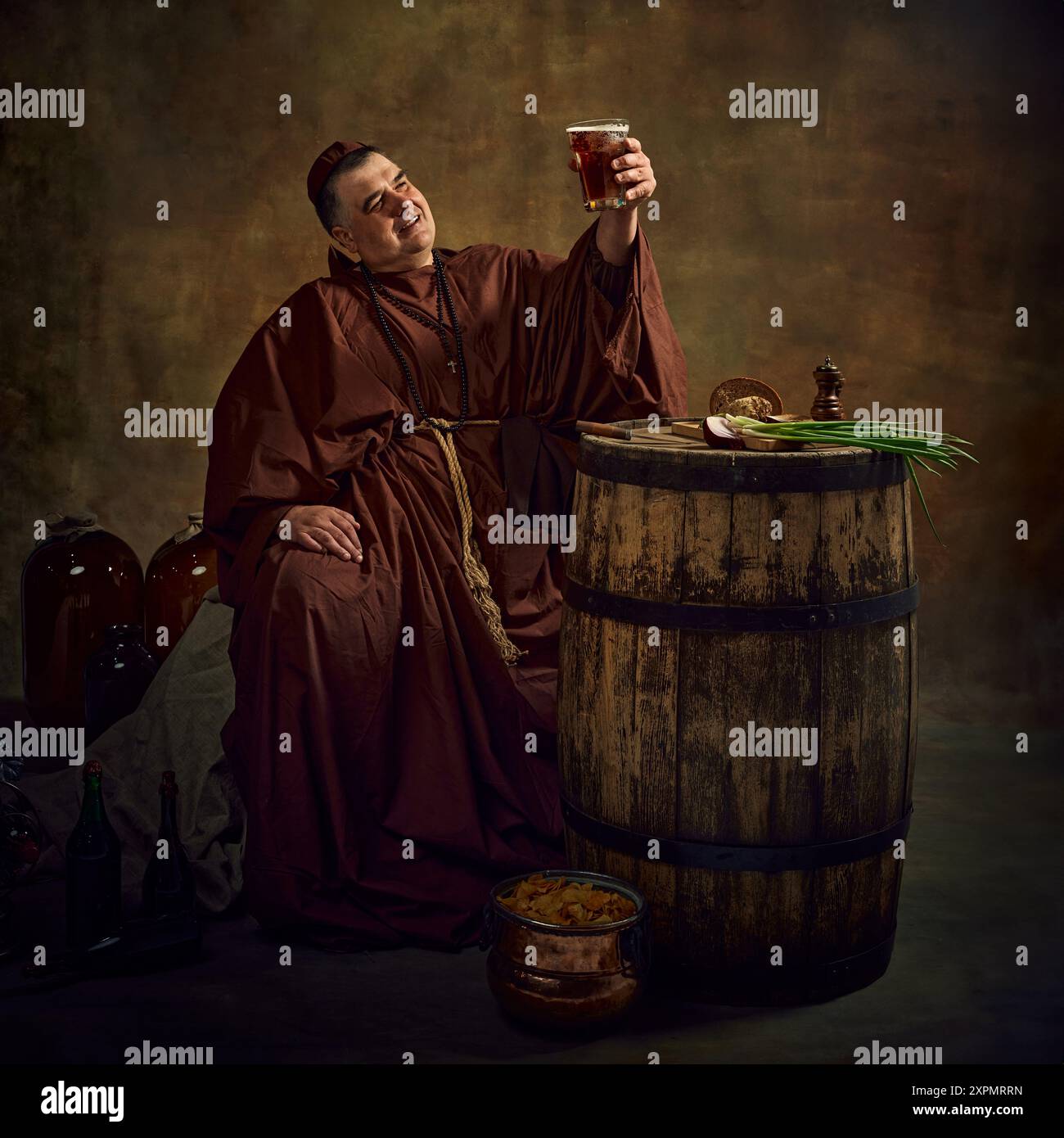 Medieval monk, man lifting pint of ale against dark vintage background ...