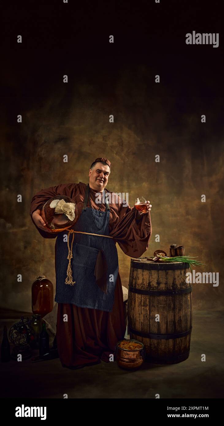 Cheerful monk holds barrel and pint of ale, beer against dark vintage ...