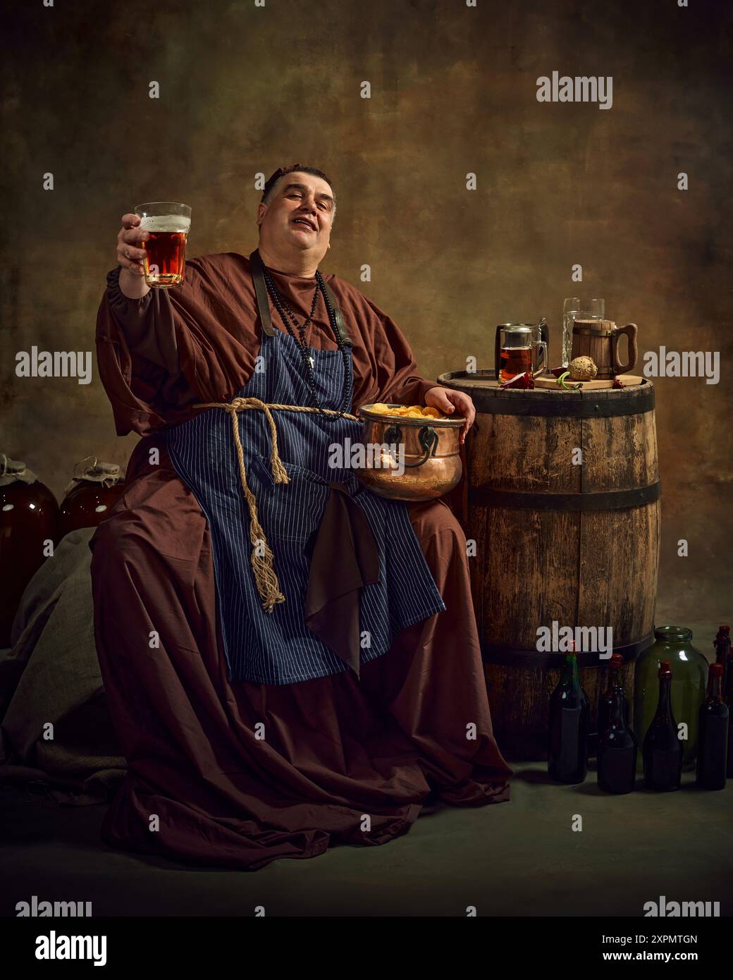 Cheers. Happy man, medieval monk rising mug with ale, eating chips ...