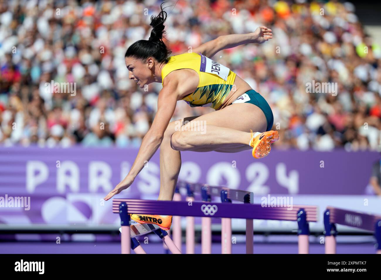 Michelle Jenneke, of Australia, knocks down a hurdle during a heat in ...