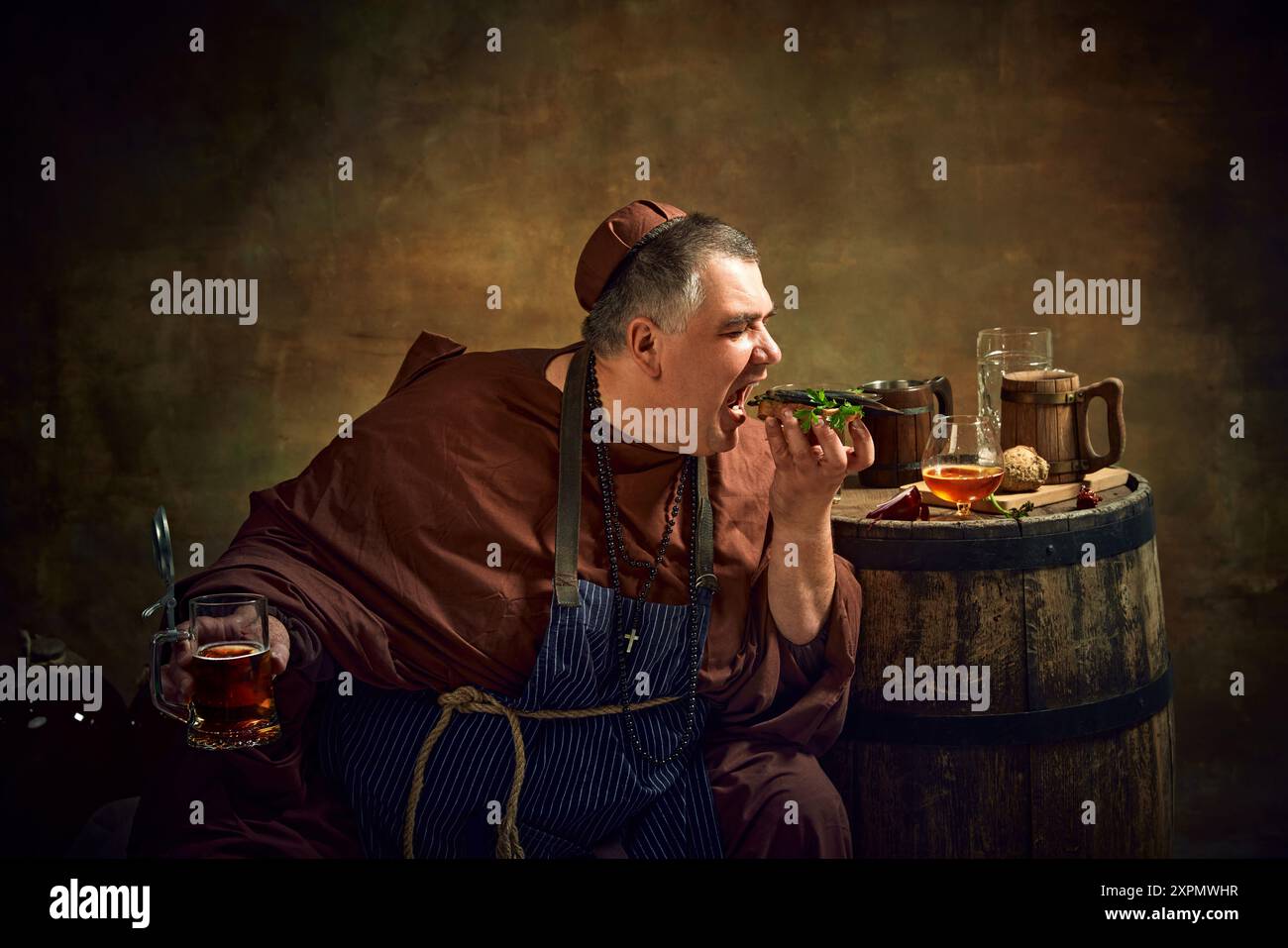 Man, monk in period attire enjoying sandwich with fish and drinking ale ...