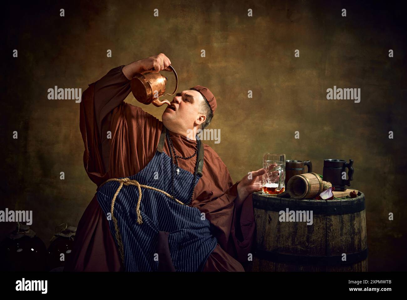 Medieval monk in period clothes drinking beer from kettle, sitting in ...