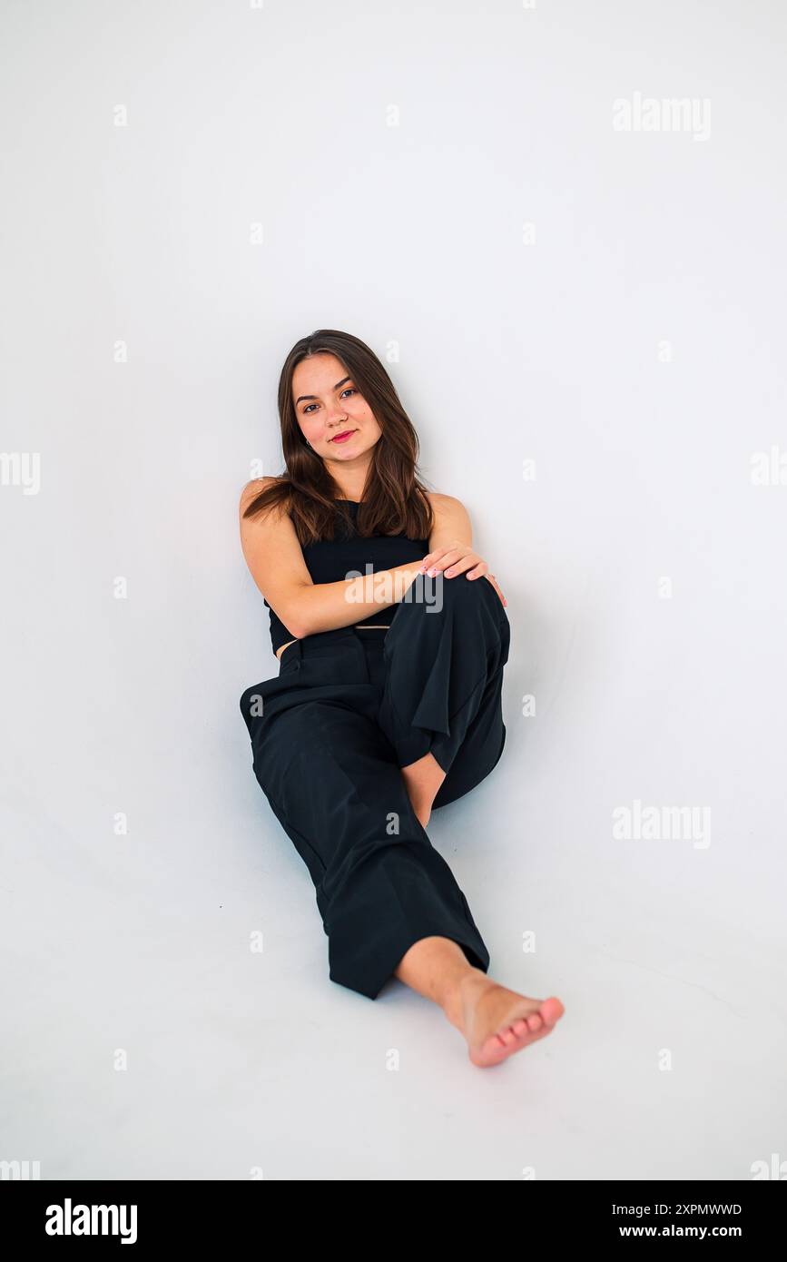 a girl sits on a white floor and stretches one leg forward Stock Photo ...