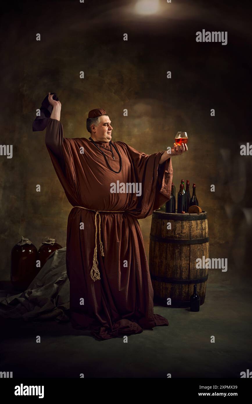 Medieval monk joyfully raising glass of ale, cognac or beer, showing ...