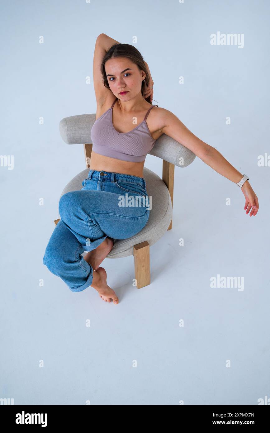 Girl Sits On A Chair With Her Legs Crossed And Her Hand Raised Stock