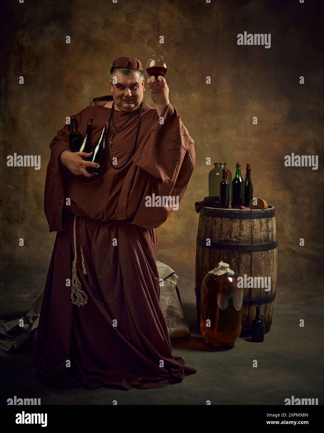 Medieval monk in period attire holding glass with cognac, beer, ale ...