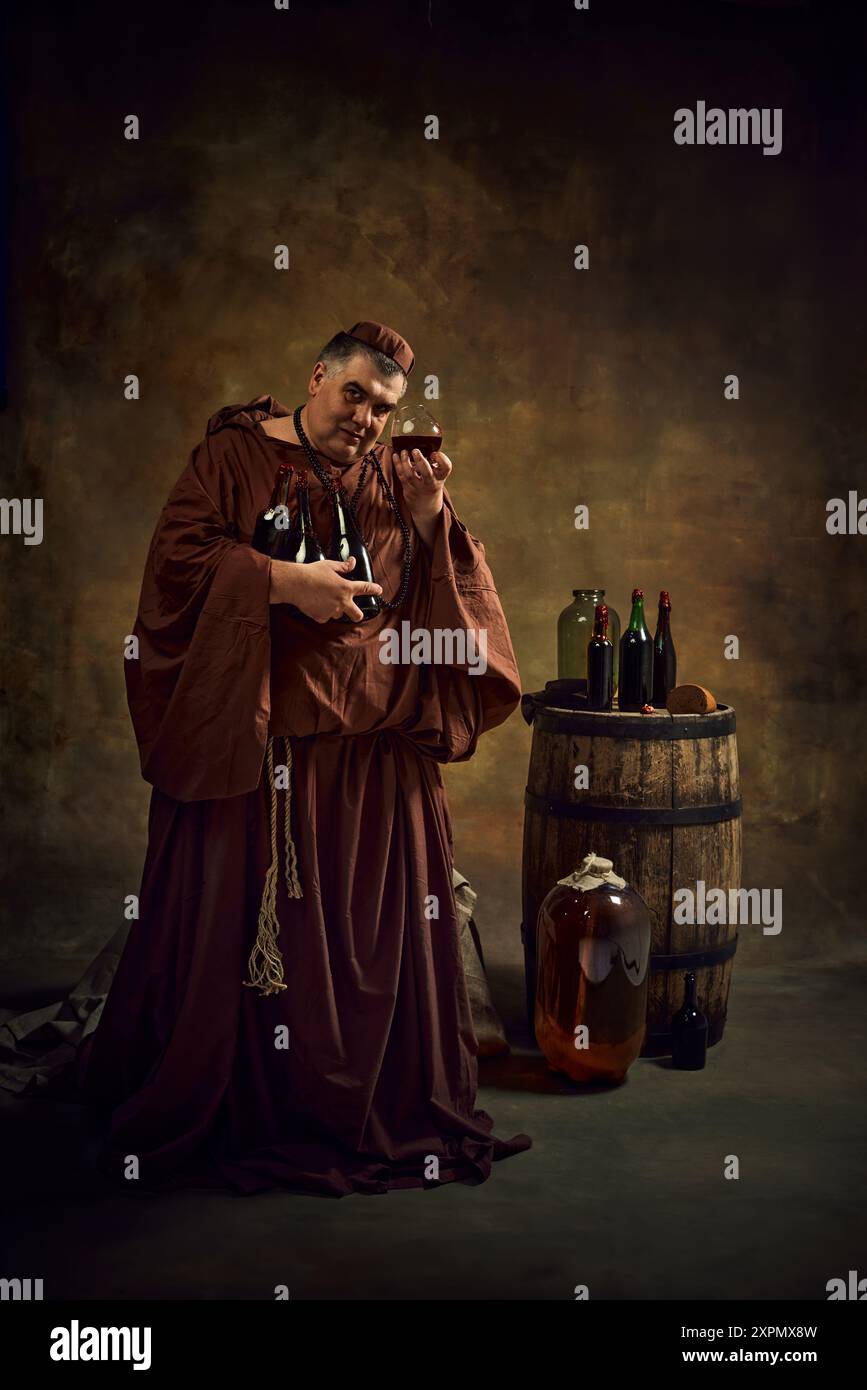 Medieval monk in period attire holding glass with cognac, beer, ale ...