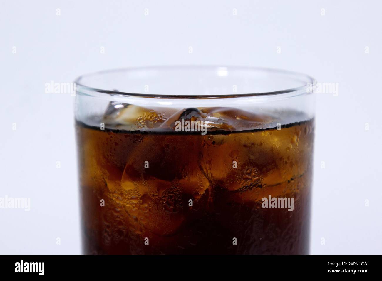An isolated glass of black cola with ice is filled on white background ...