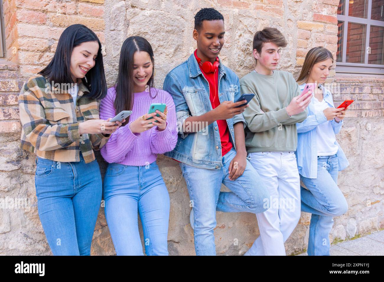 Five students having fun with mobile phones creating content on social ...