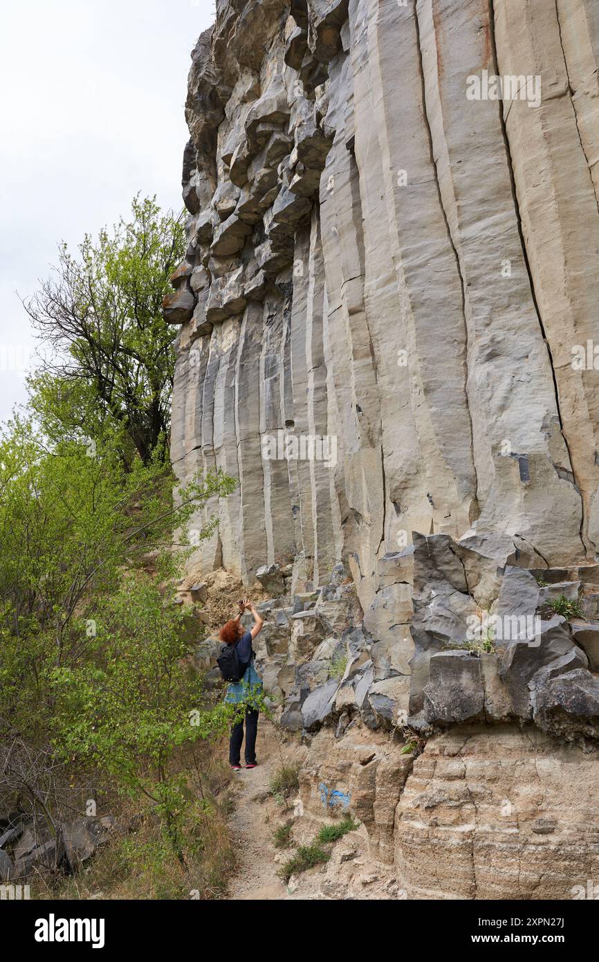 Woman tourist photographing various rock formations of basalt ...