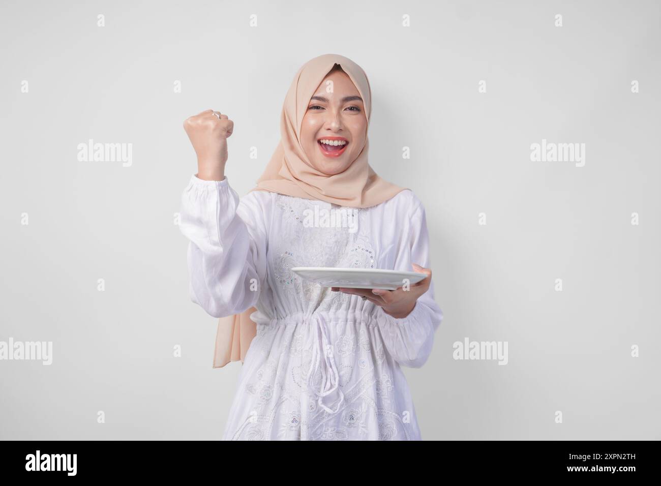 Cheerful young Asian Muslim woman in hijab doing a successful win ...
