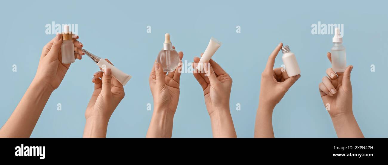 Hands holding different cosmetic products on light blue background ...
