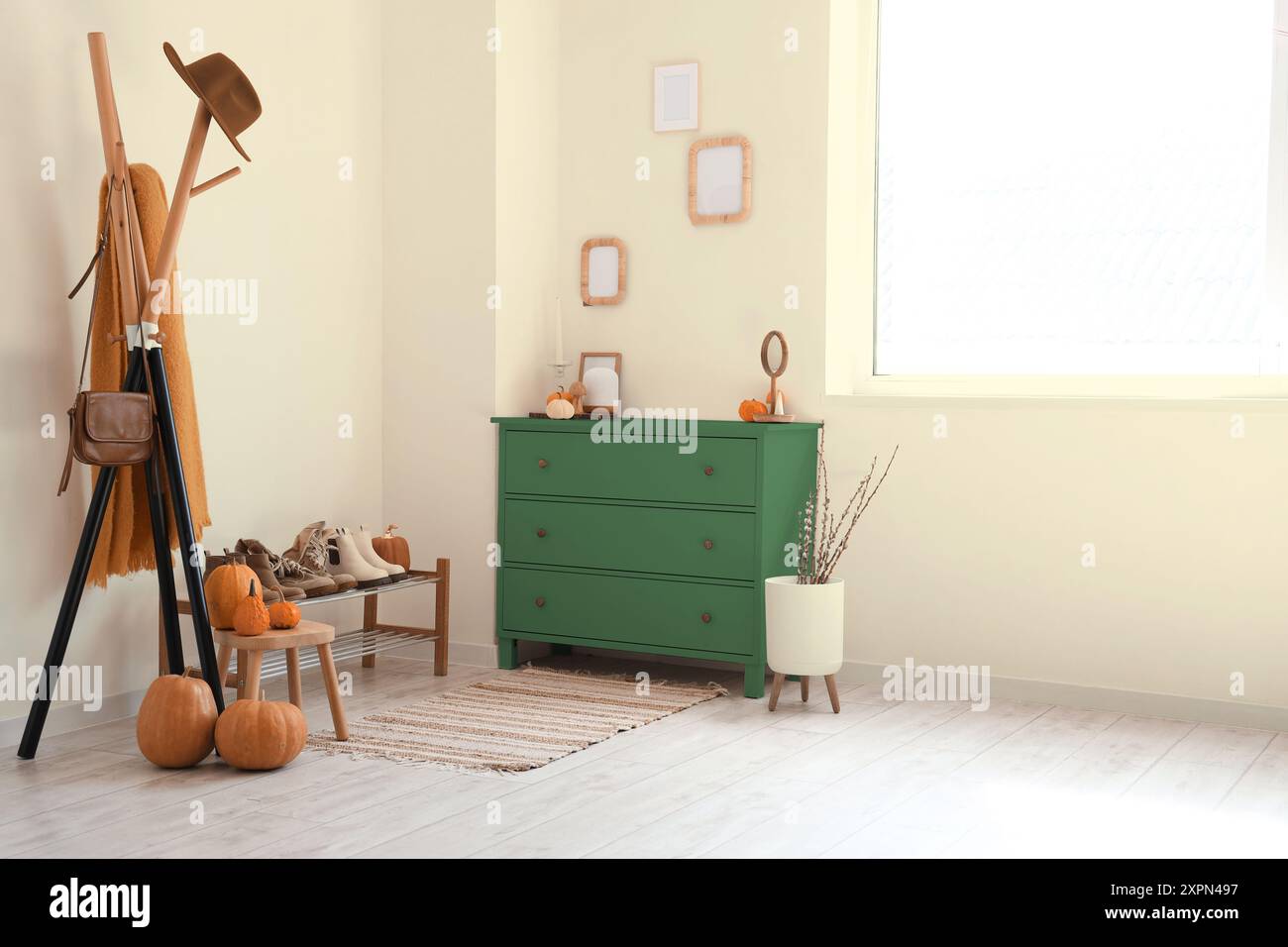 Interior of cozy hall with pumpkins, clothes rack, chest of drawers and ...