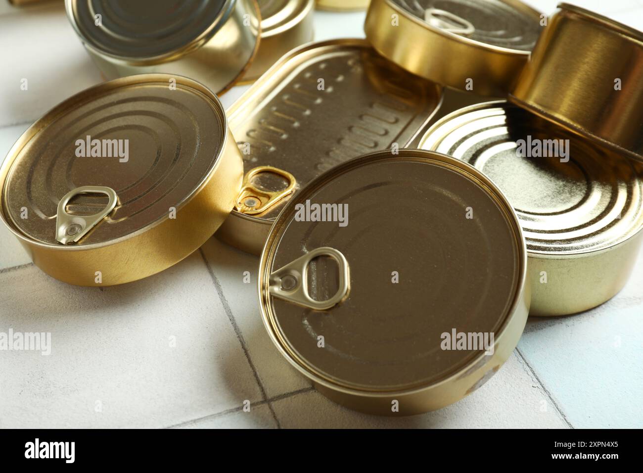 Different tin cans with fish on tiled table Stock Photo - Alamy
