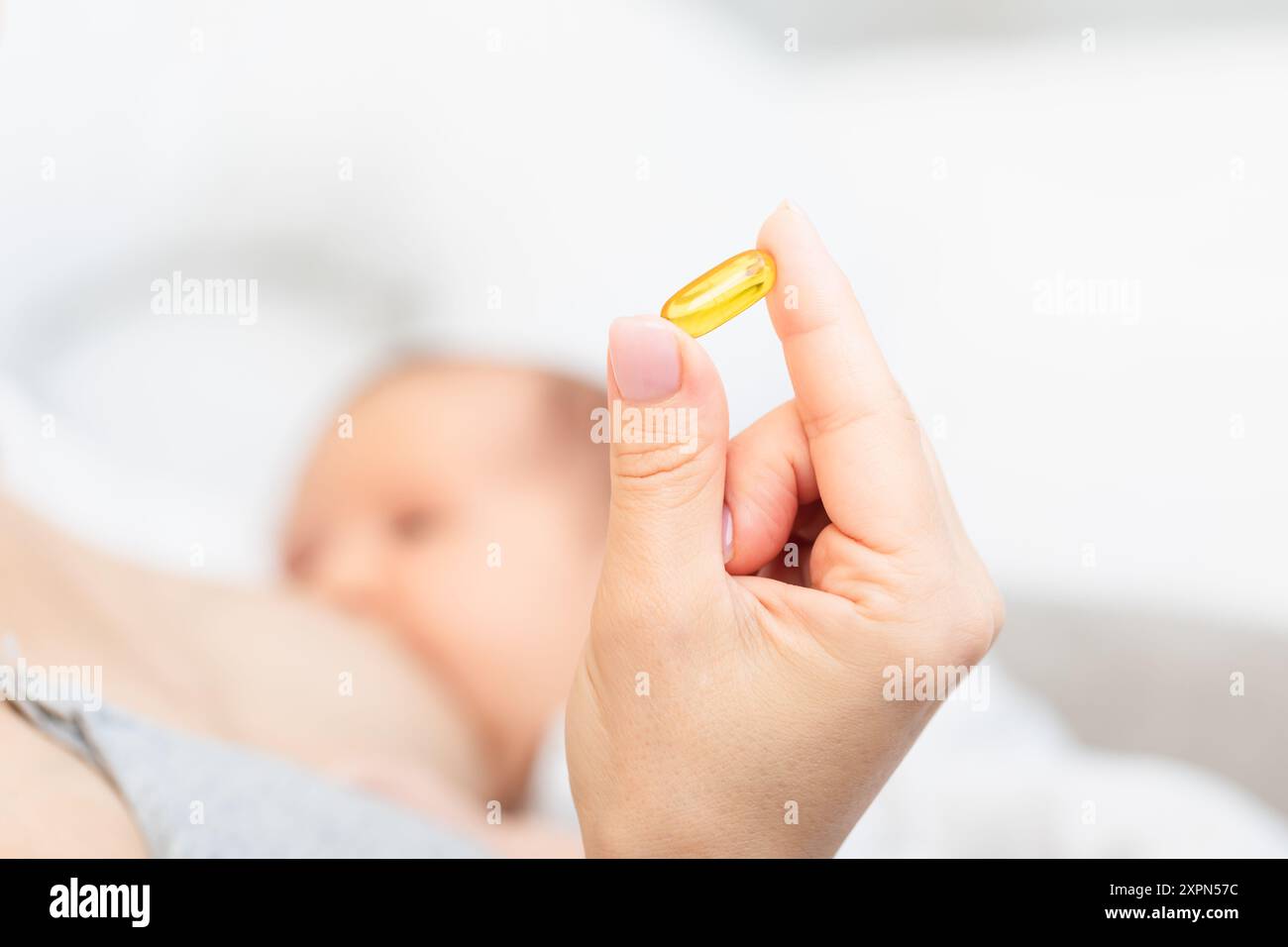 Mother holding yellow pill while breastfeeding newborn baby ...