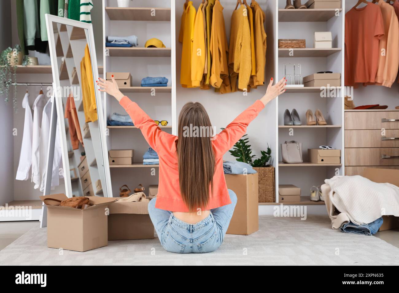 Beautiful young woman with wardrobe boxes and stylish clothes sitting ...