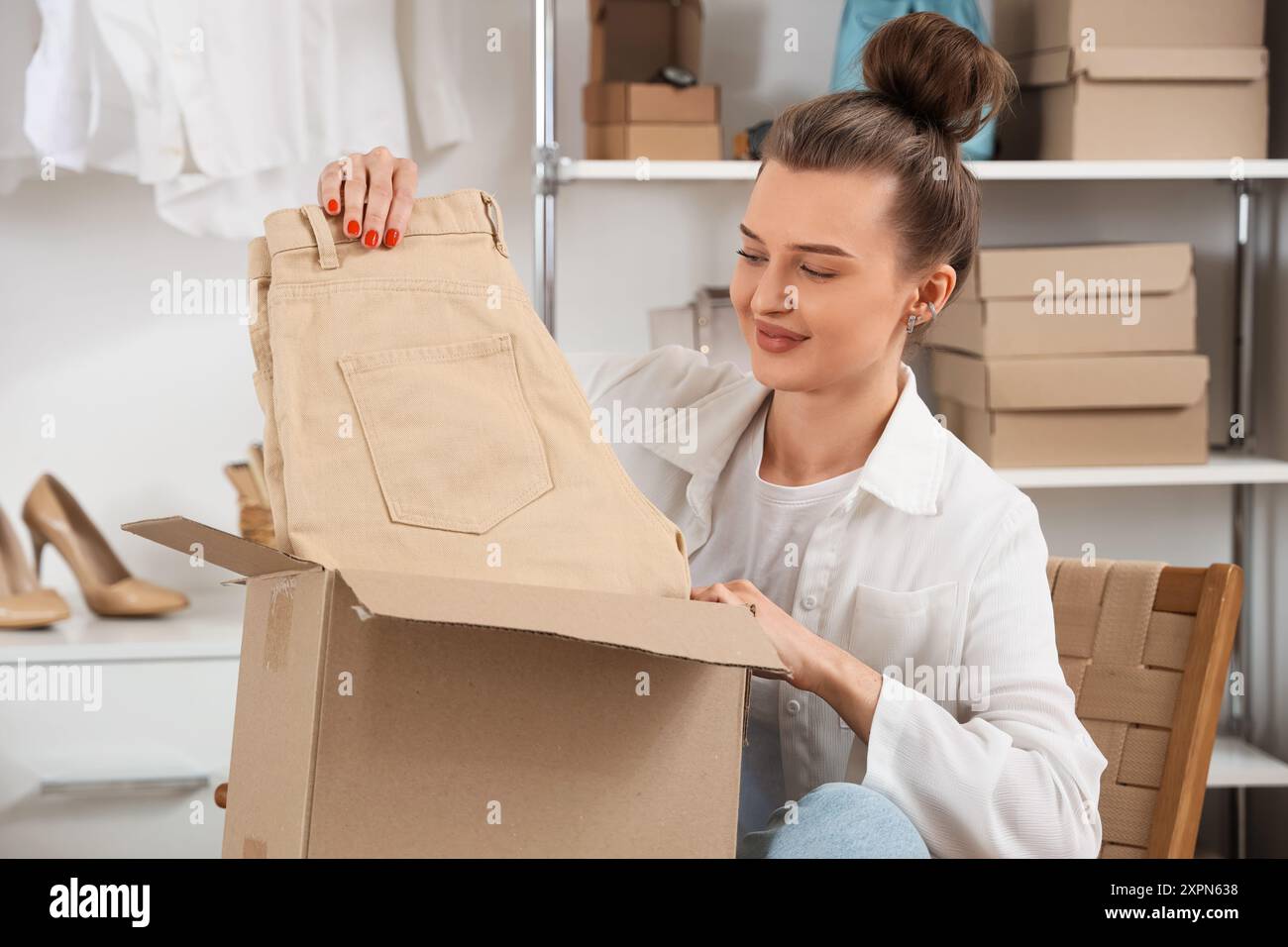 Beautiful young happy woman unpacking wardrobe boxes with stylish ...