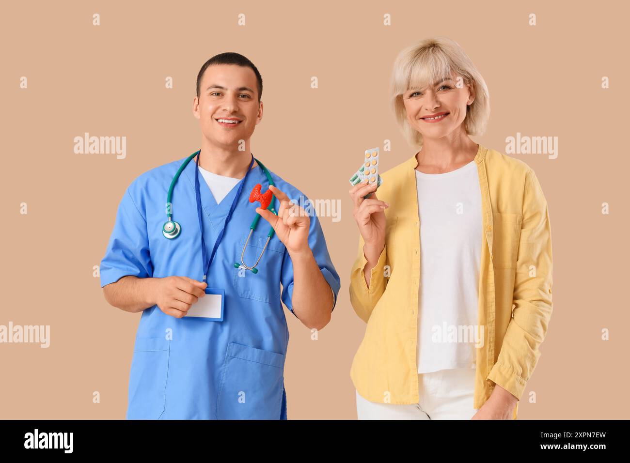 Male endocrinologist with thyroid gland model and mature woman on beige ...
