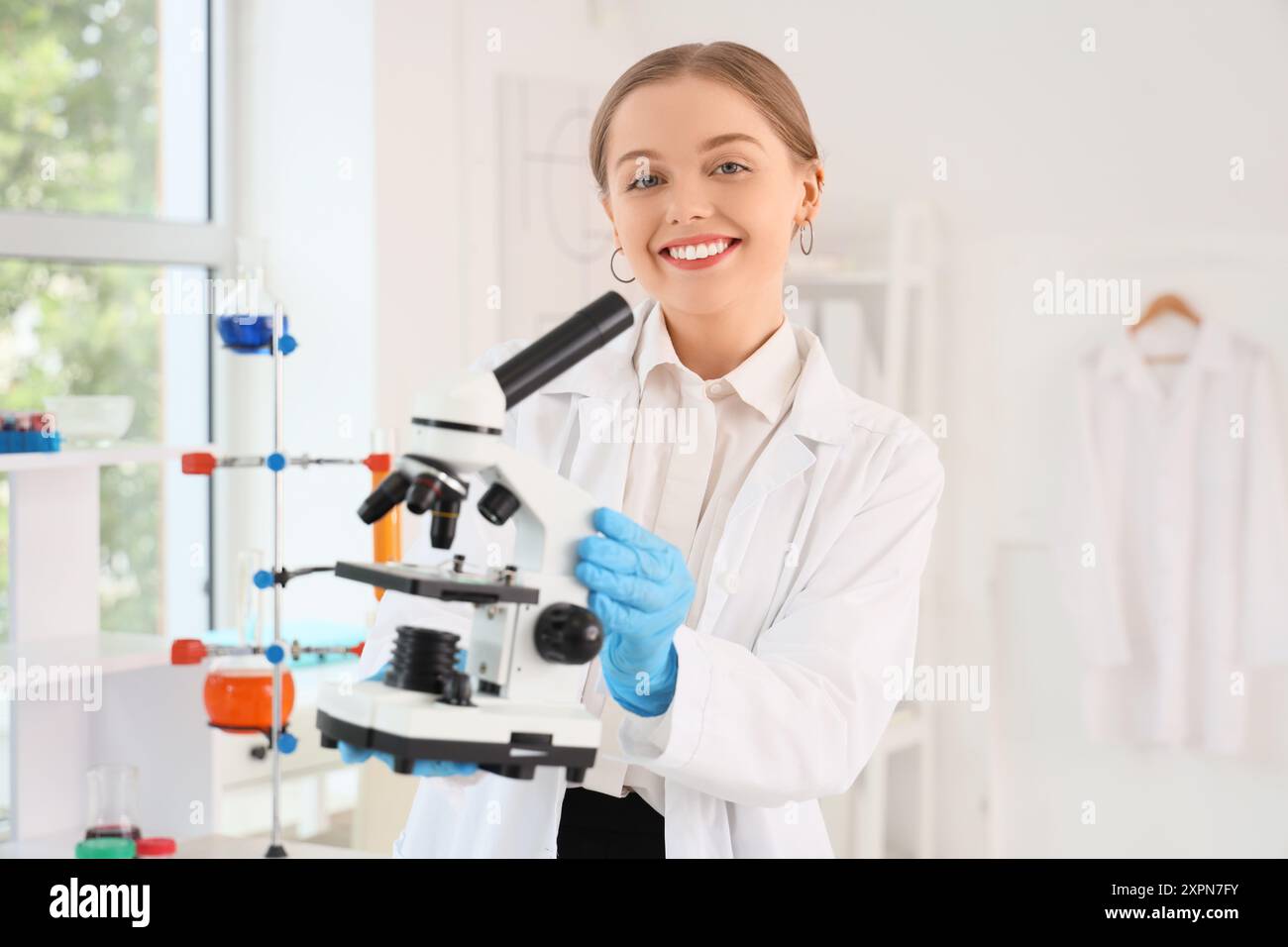 Female chemist with microscope in laboratory Stock Photo - Alamy