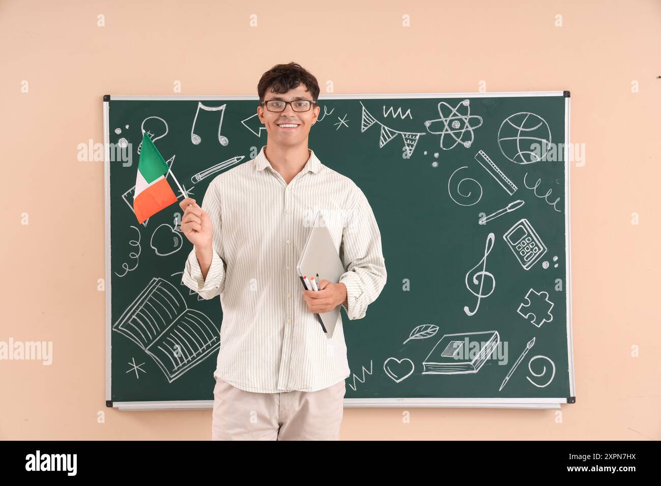 Male Italian teacher with flag and laptop near blackboard in classroom ...