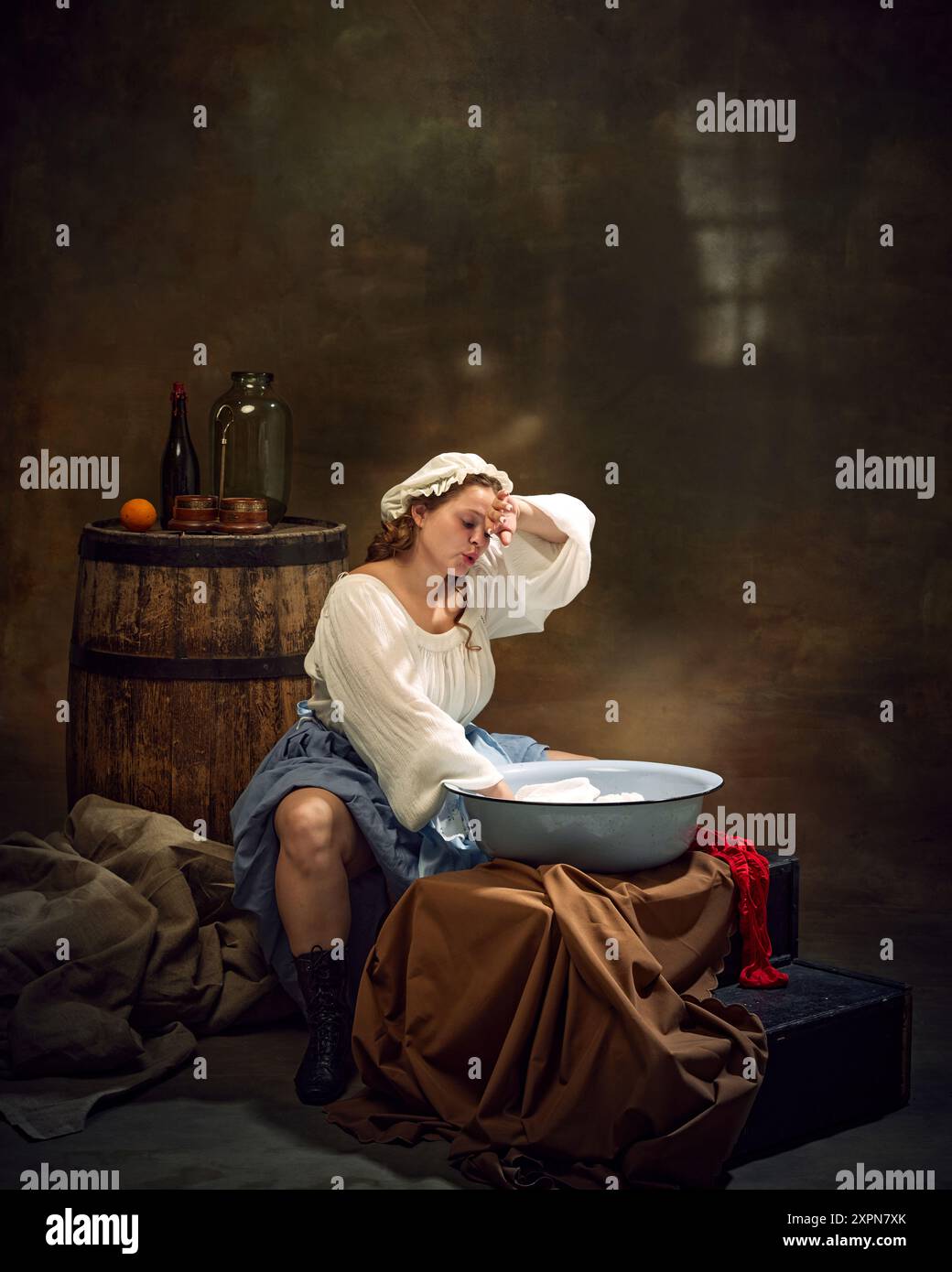 Medieval woman in traditional attire sits wearily by basin, washing ...
