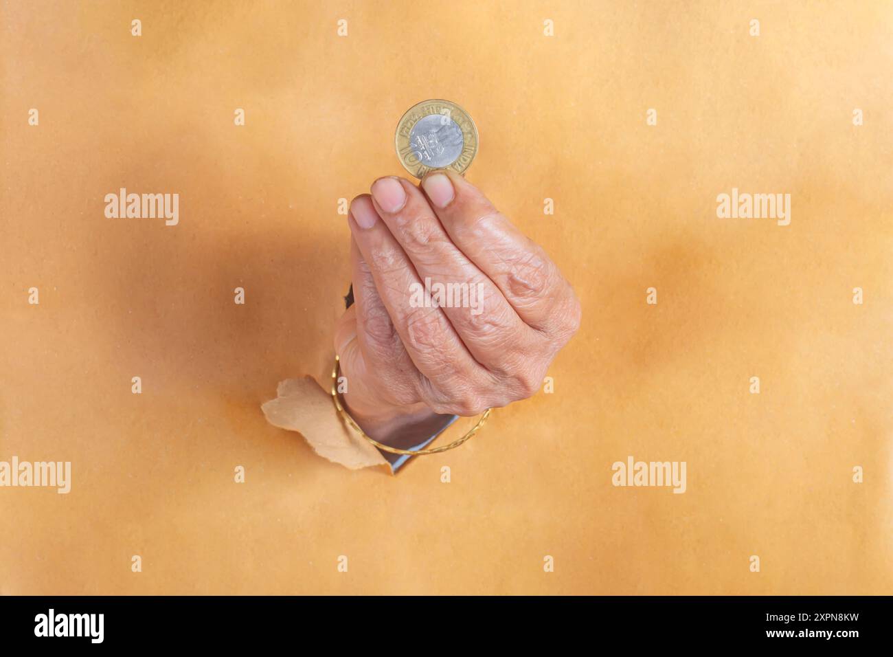 Senior woman hand holding indian 10 rupees coin that comes out tearing ...