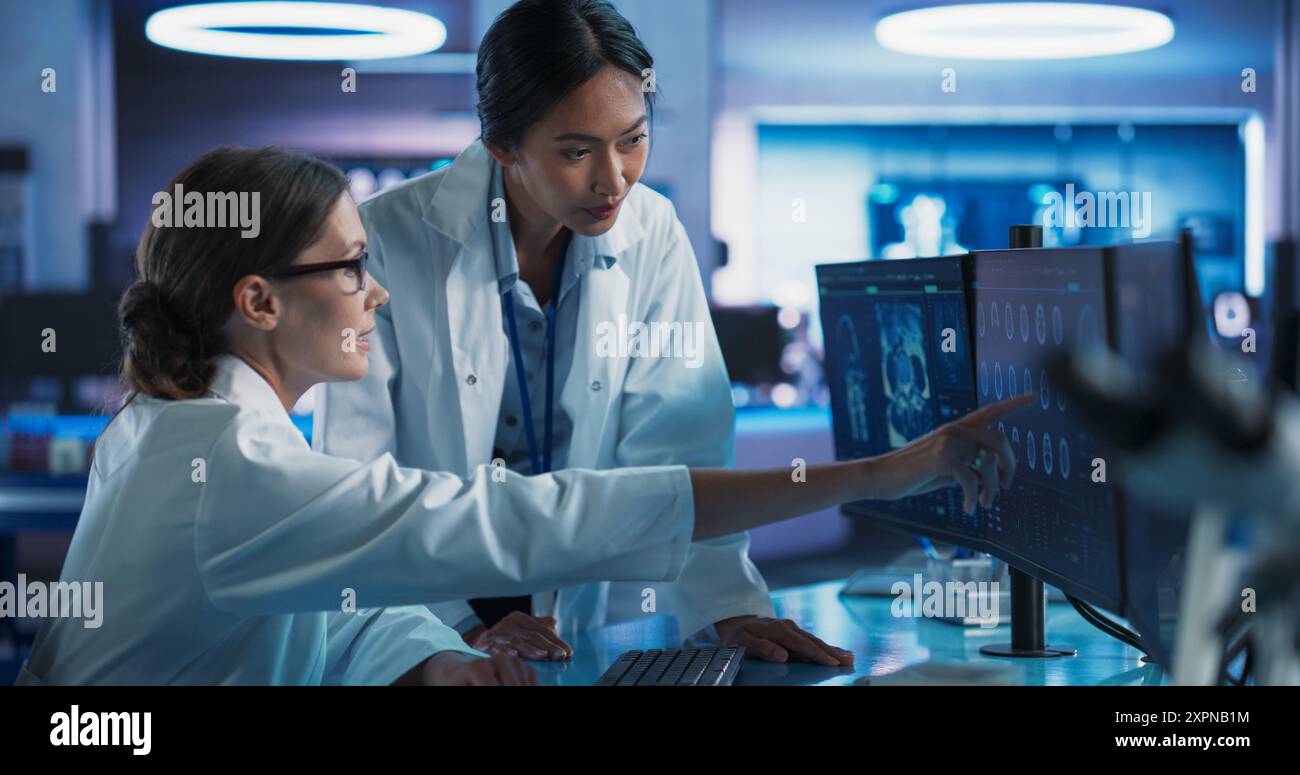 Asian And Caucasian Female Doctors Talking In Medical Research Center And Using Desktop Computer ...