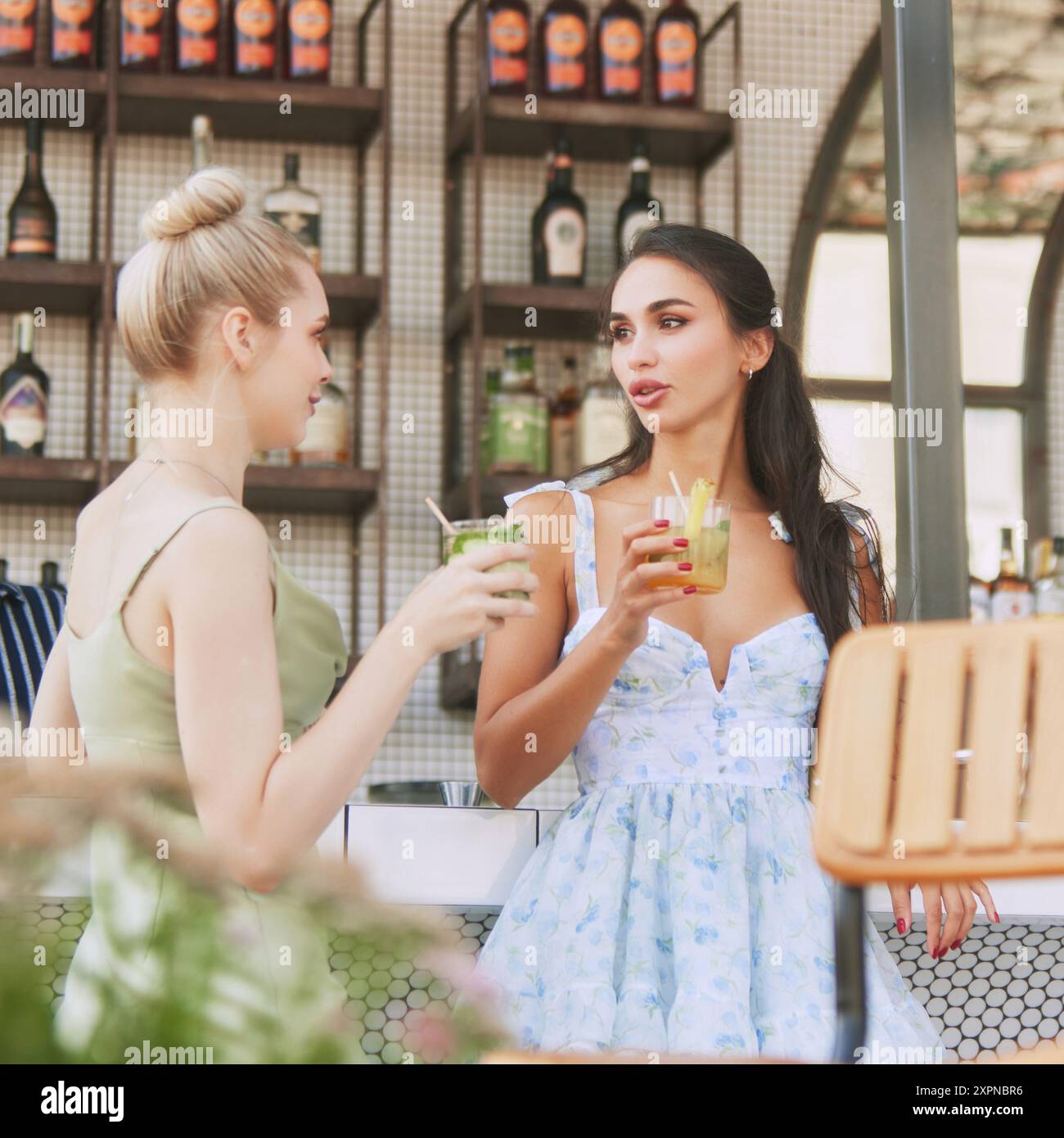 Two young beautiful women in dresses involved in deep conversation ...