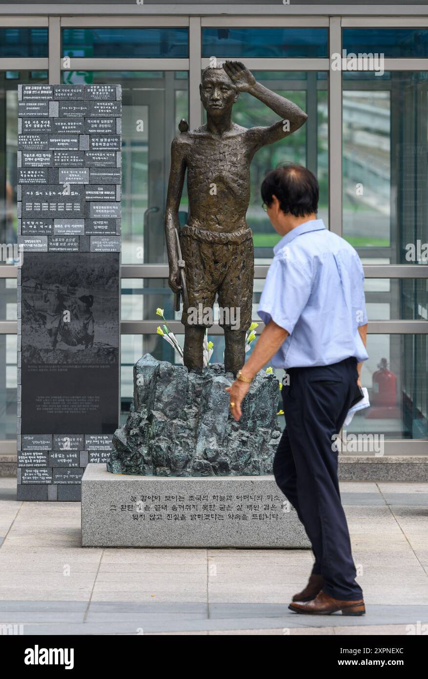 People pass in front of a statue of a forced labor worker in Japanese ...