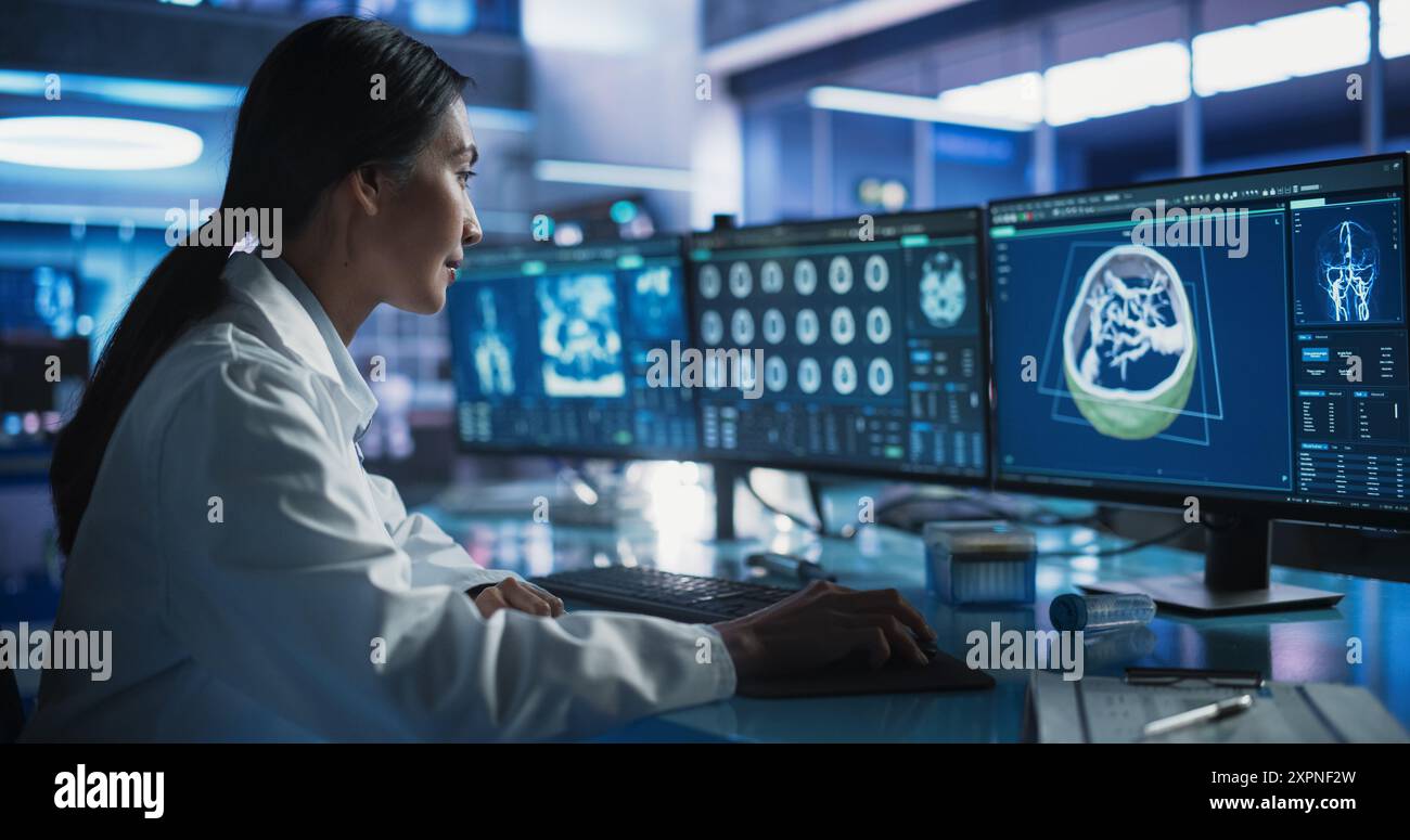 Female Asian Neurologist Using Desktop Computer With Human Brain MRI Scans In Modern Medical ...