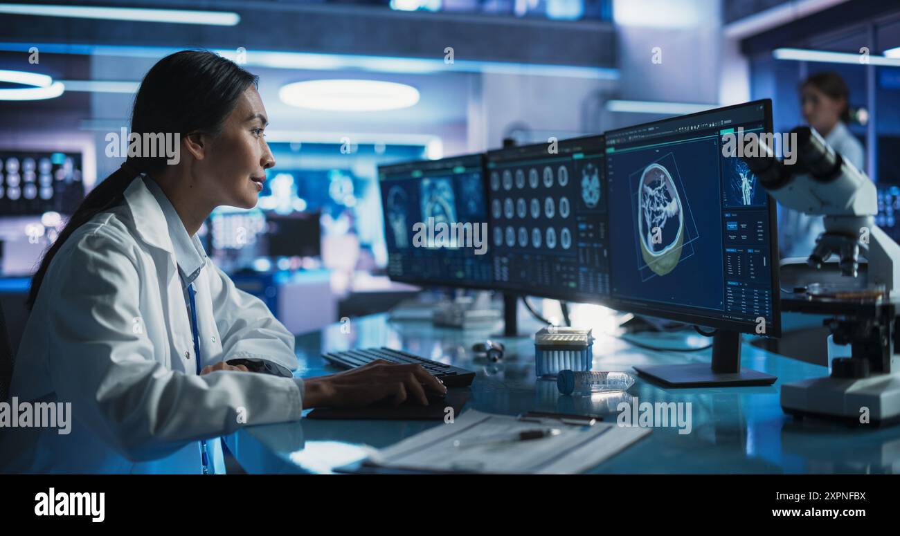 Female Asian Neuroscientist Using Desktop Computer With Human Brain CT Scans In Modern Medical ...