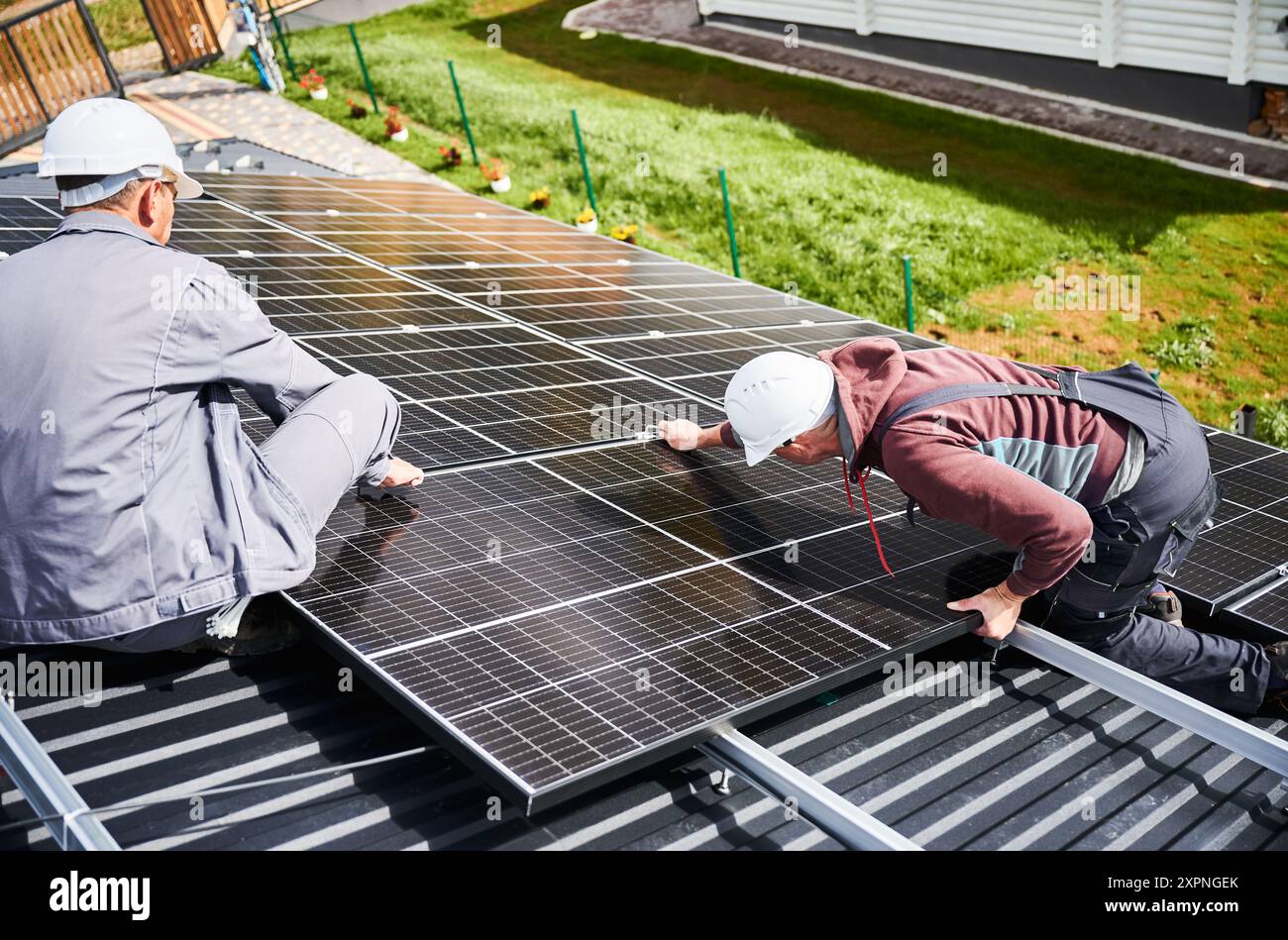 Engineers installing photovoltaic solar panels on roof of house. Men ...