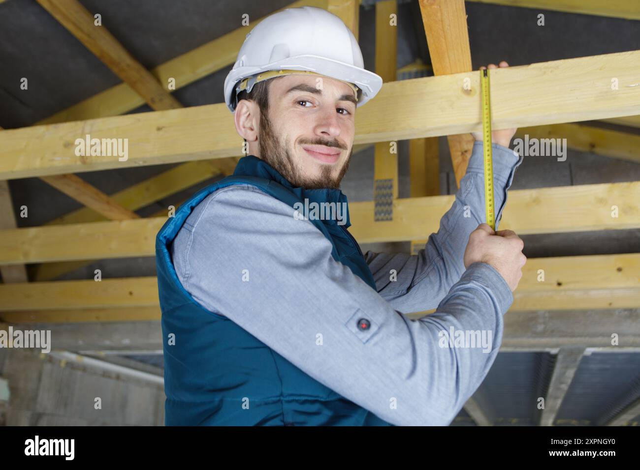portrait of construction worker measuring planks at construction site ...