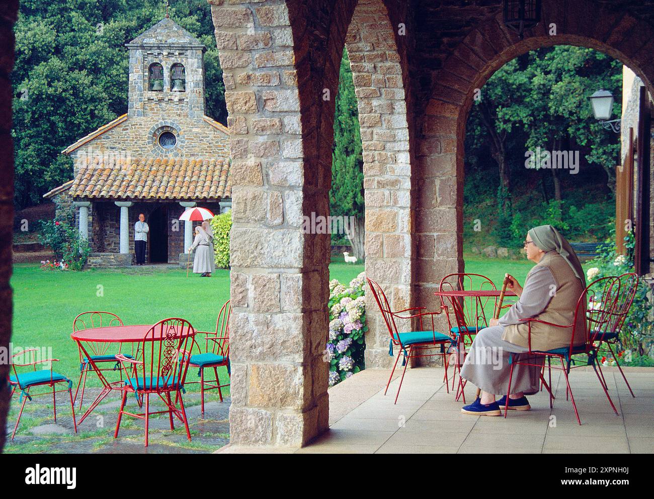 Nun sitting in a terrace by Sant Bernat church. Montseny Nature Reserve ...
