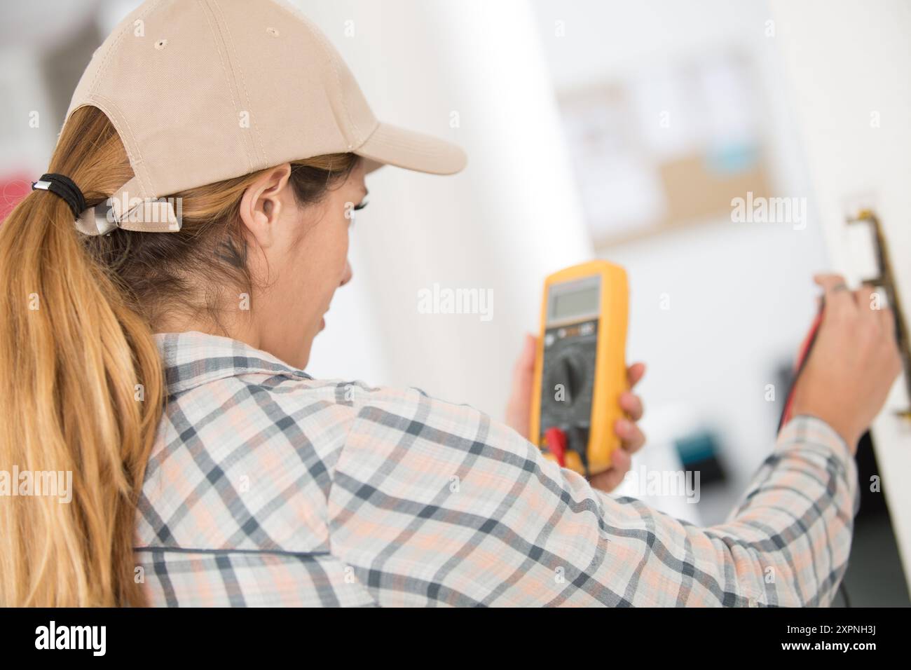 female electrician measures the voltage in the home network Stock Photo ...