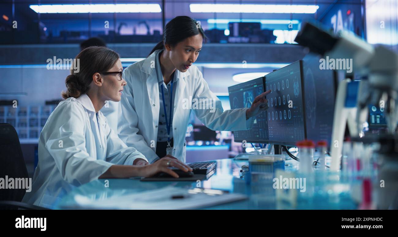Asian And Caucasian Female Doctors Talking In Medical Research Center And Using Desktop Computer ...