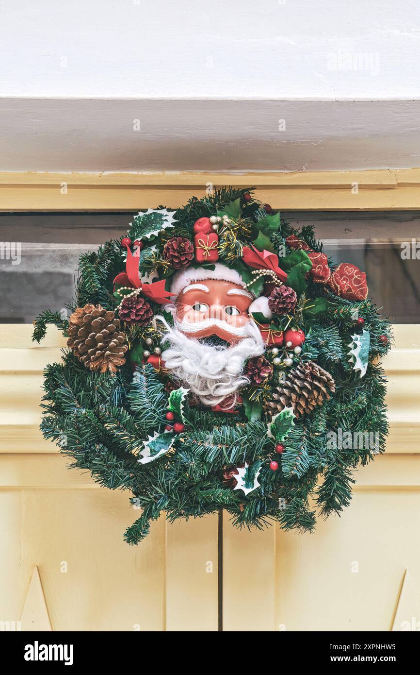 Traditional green and red Christmas crown with face of Santa Claus hung ...