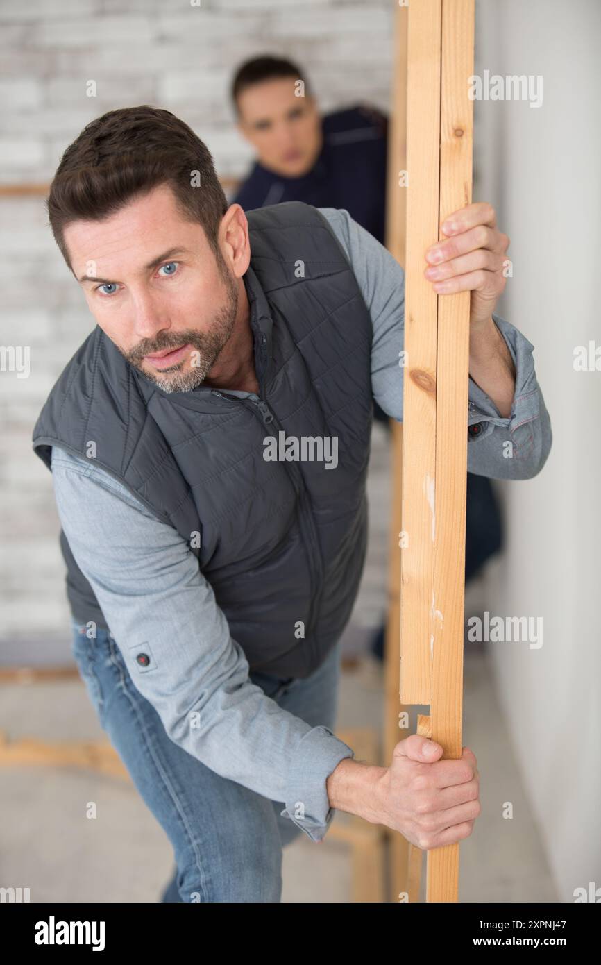 building team carrying a notched out wooden framework Stock Photo - Alamy