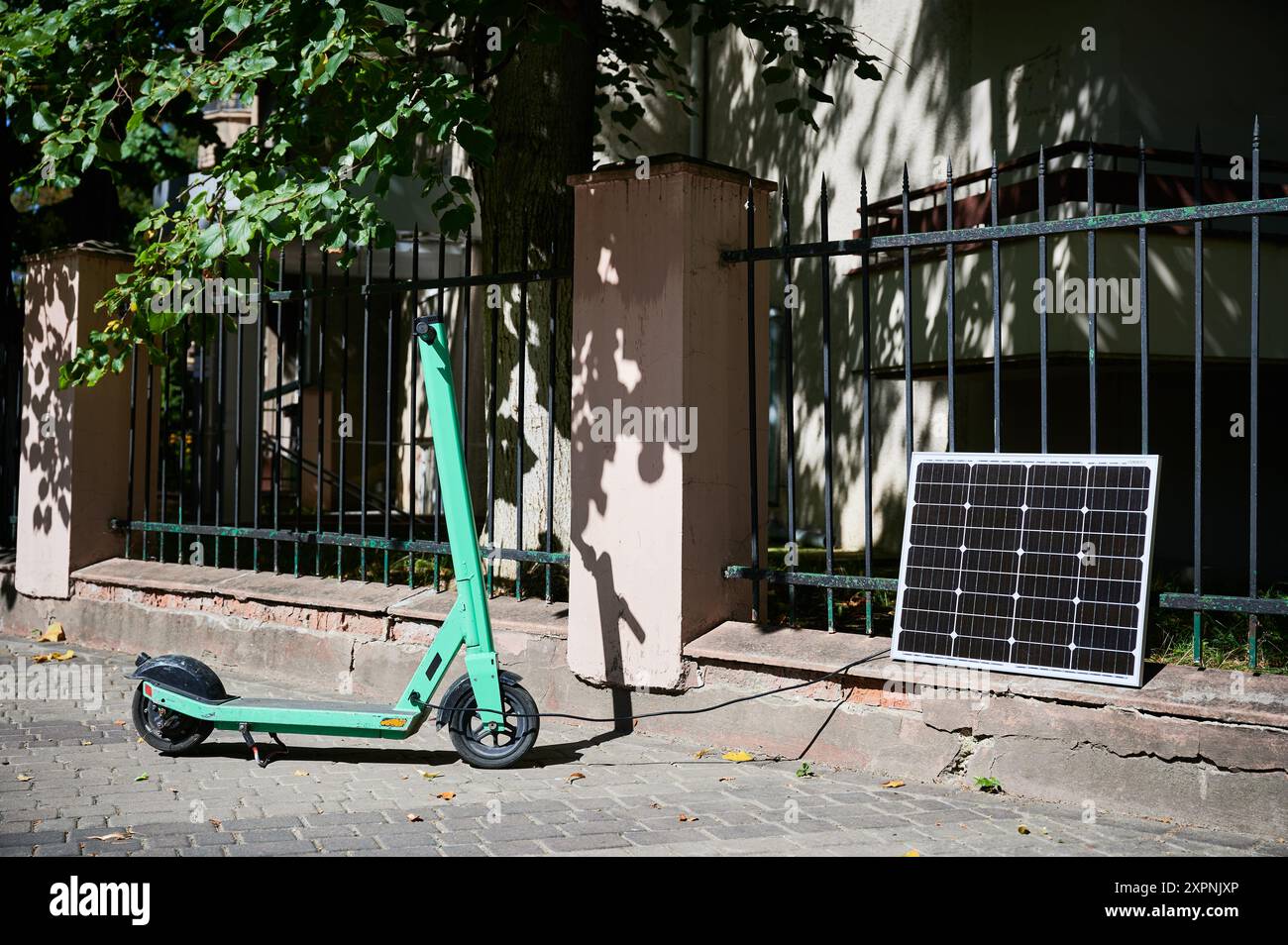 Mint-green electric scooter parked on stone pavement next to solar ...