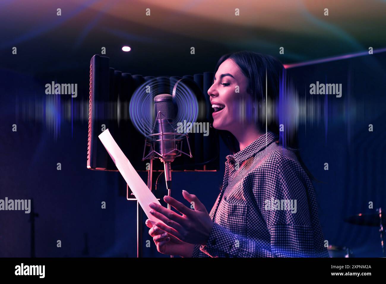 Young singer with microphone recording song in studio, color toned ...