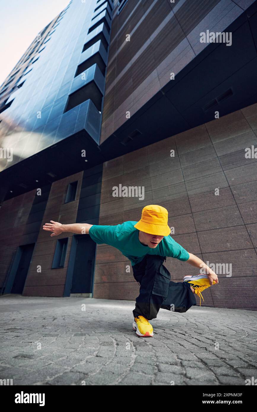 Young man, fashionista in colorful attire, breakdancer posing against ...